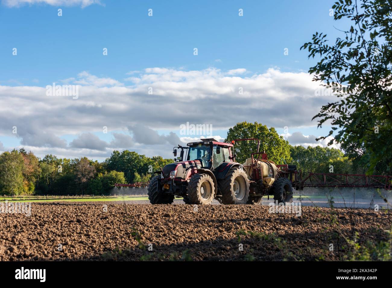 Ein Bauer mit Trecker beim besprühen des frisch gepflügten Bodens Stock ...