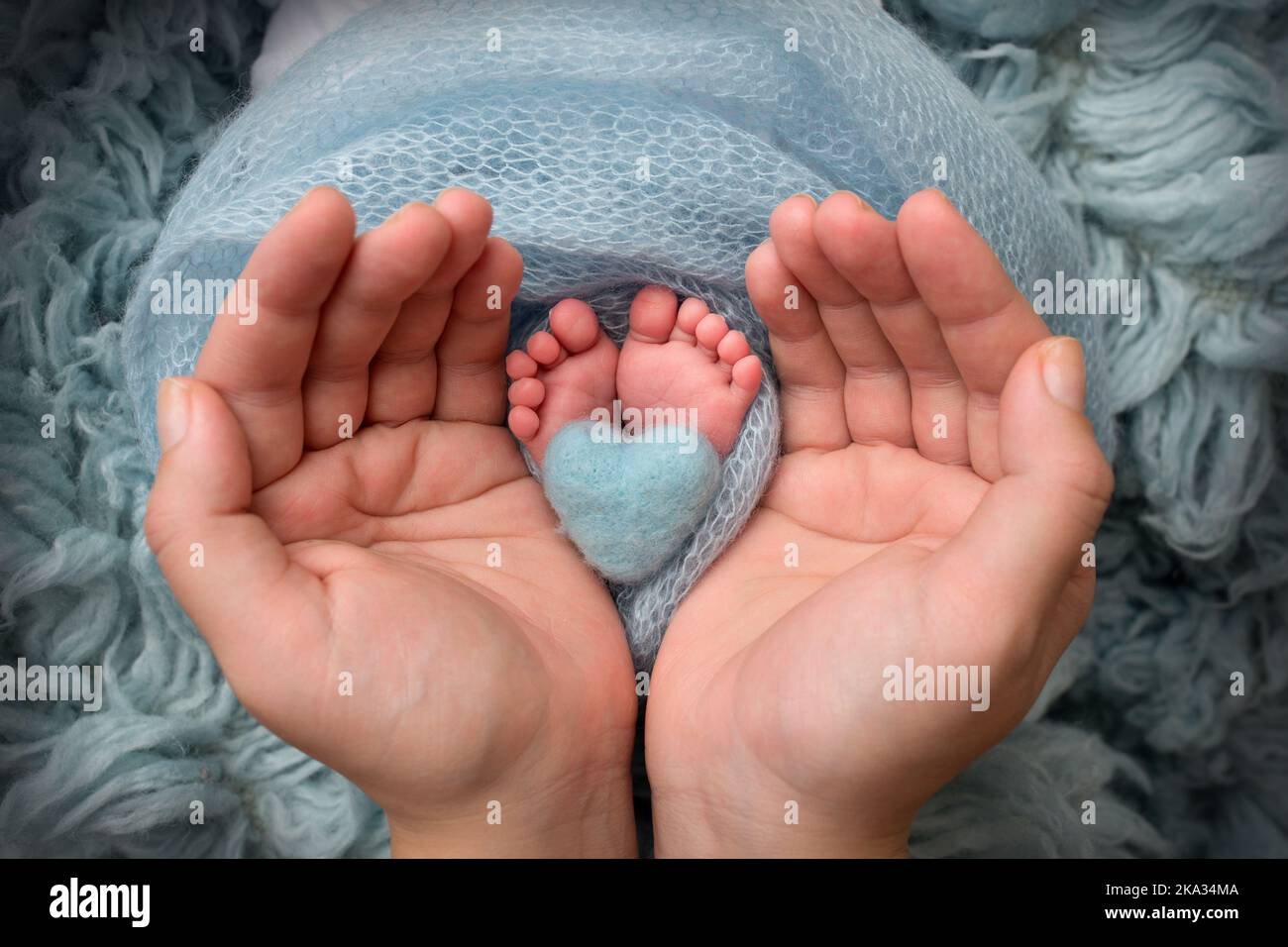 The palms of the father, the mother hold the legs of the newborn. The ...