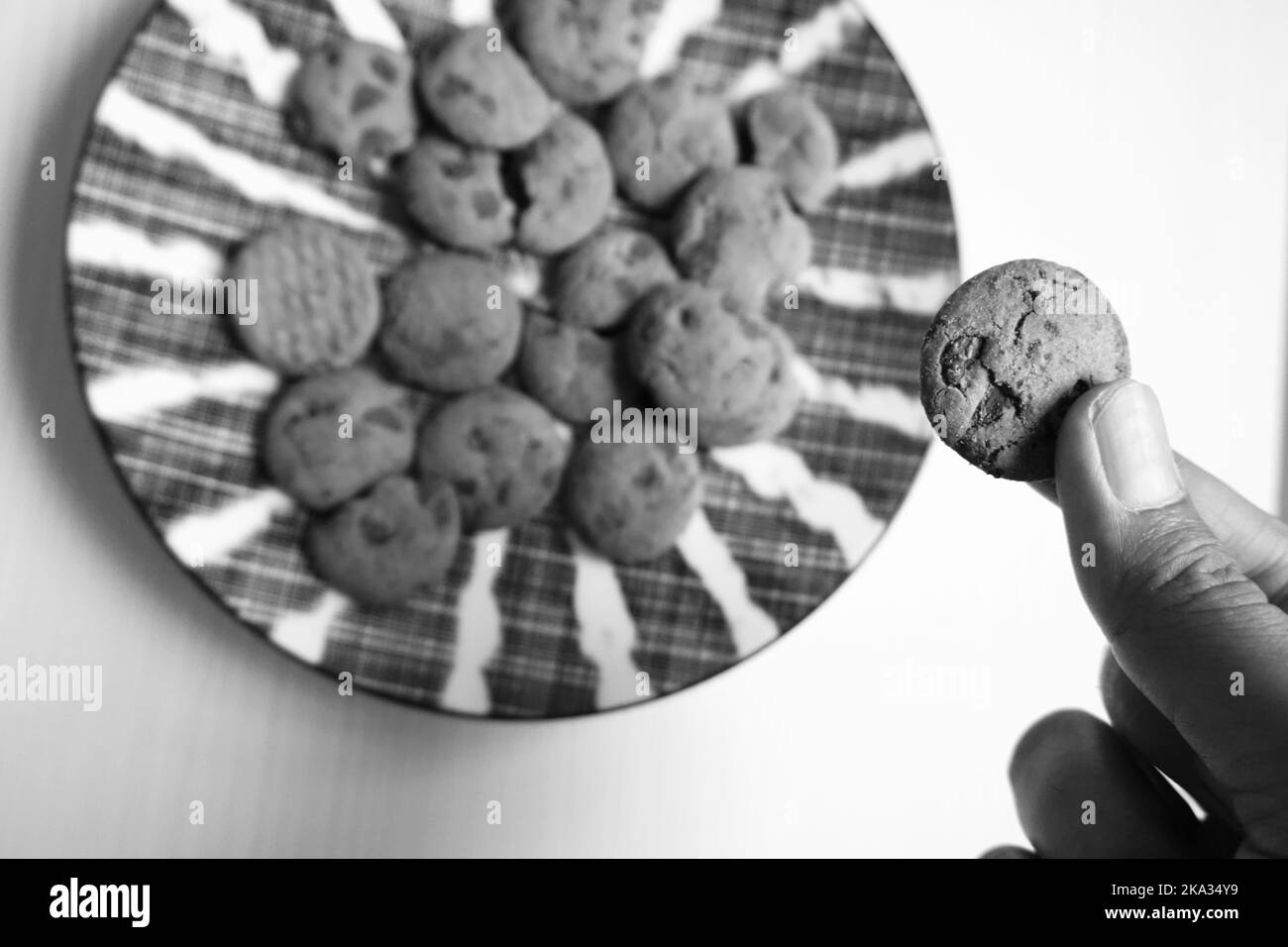 A grayscale of a hand holding a cookie Stock Photo - Alamy