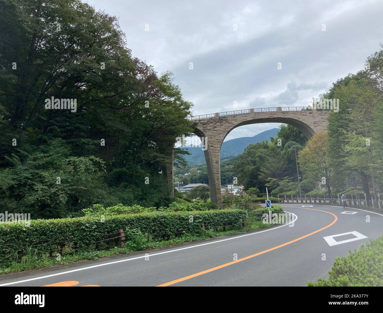 A stone bridge over an open road surrounded with greenery Stock Photo ...