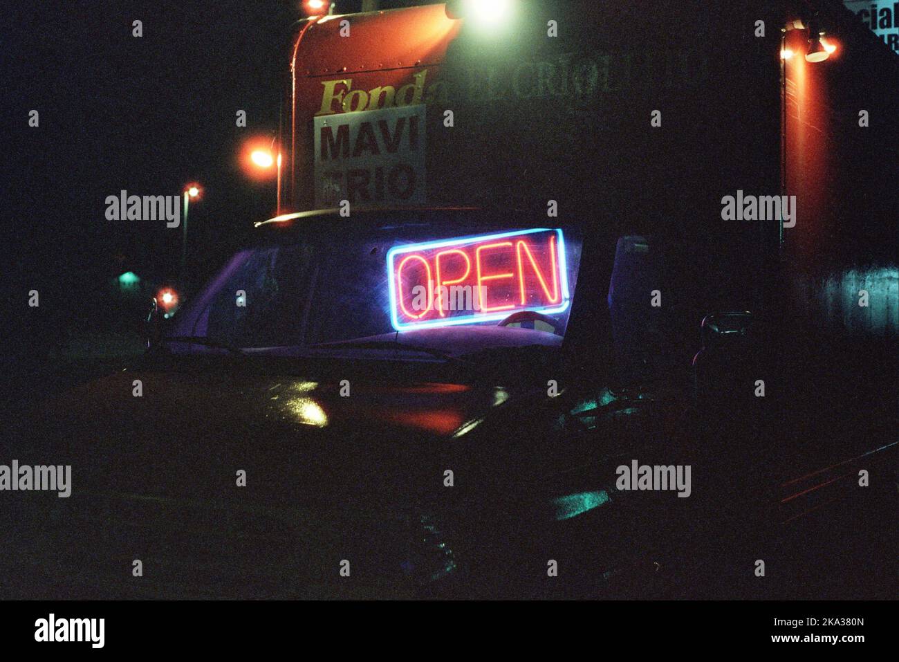 A view of car with neon ' open' sign in street Stock Photo - Alamy