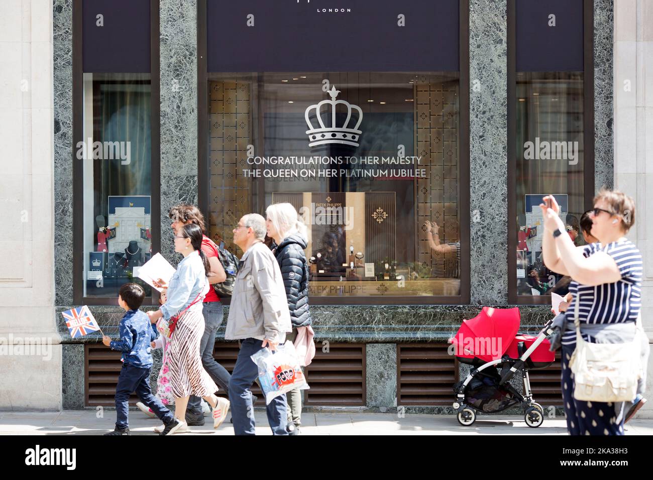 People walk past a Platinum Jubilee decoration on the window of a ...