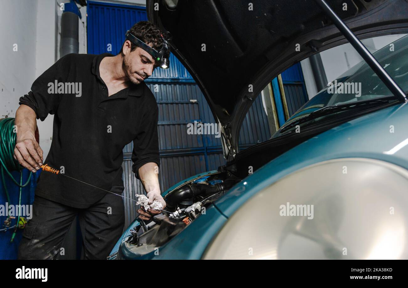 Mechanic checking engine oil dipstick Stock Photo - Alamy