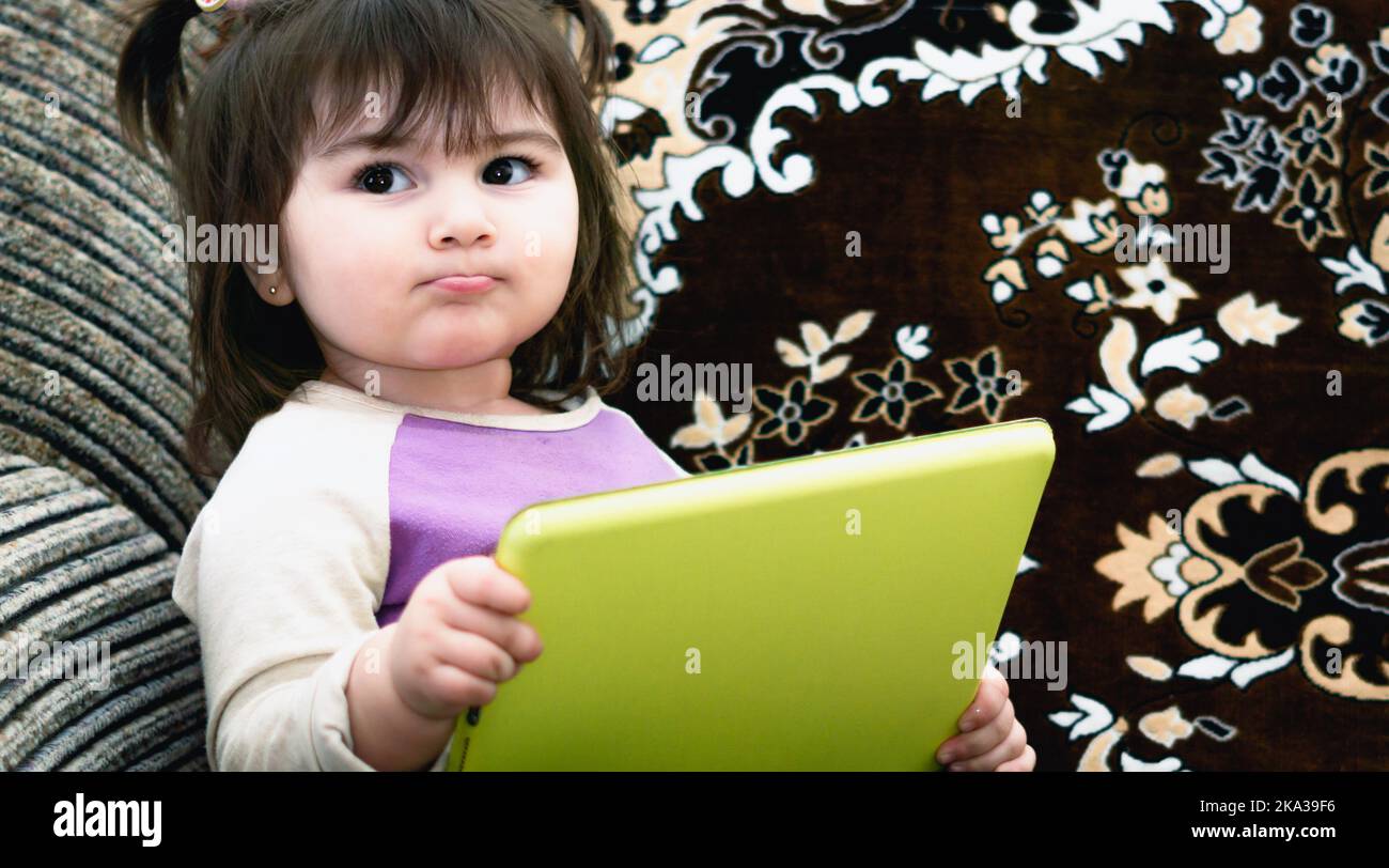 A close up adorable little baby using tablet, listening to music with ...
