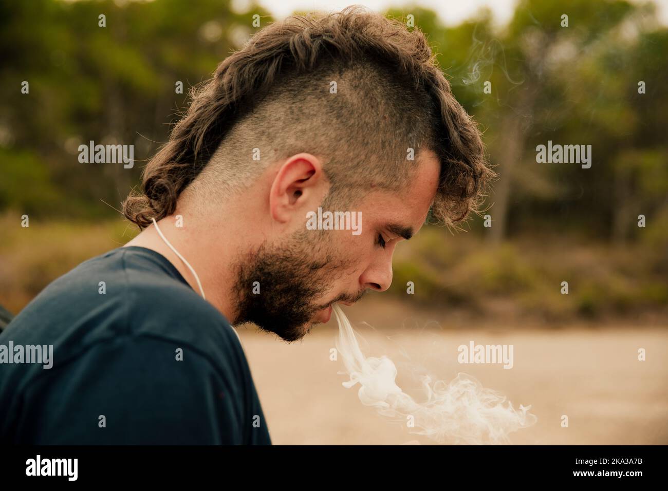 Young guy smoking a marijuana joint while looking down Stock Photo - Alamy