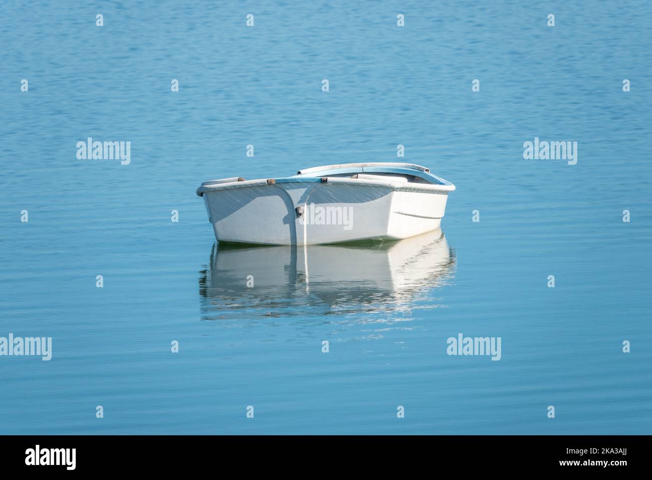 small blue and white boat in the water with reflection Stock Photo - Alamy