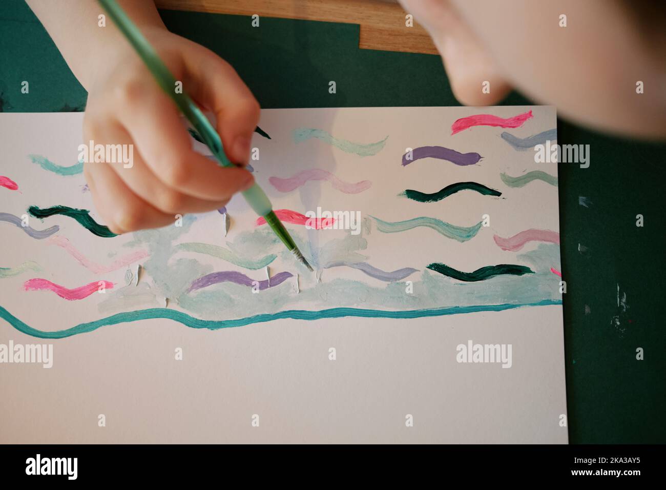 Kid painting sea waves on paper Stock Photo - Alamy