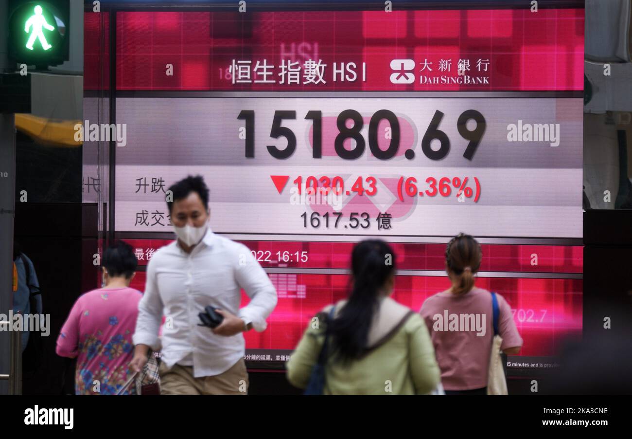 Pedestrians walk past an electronic billboard displaying the Hang Seng ...