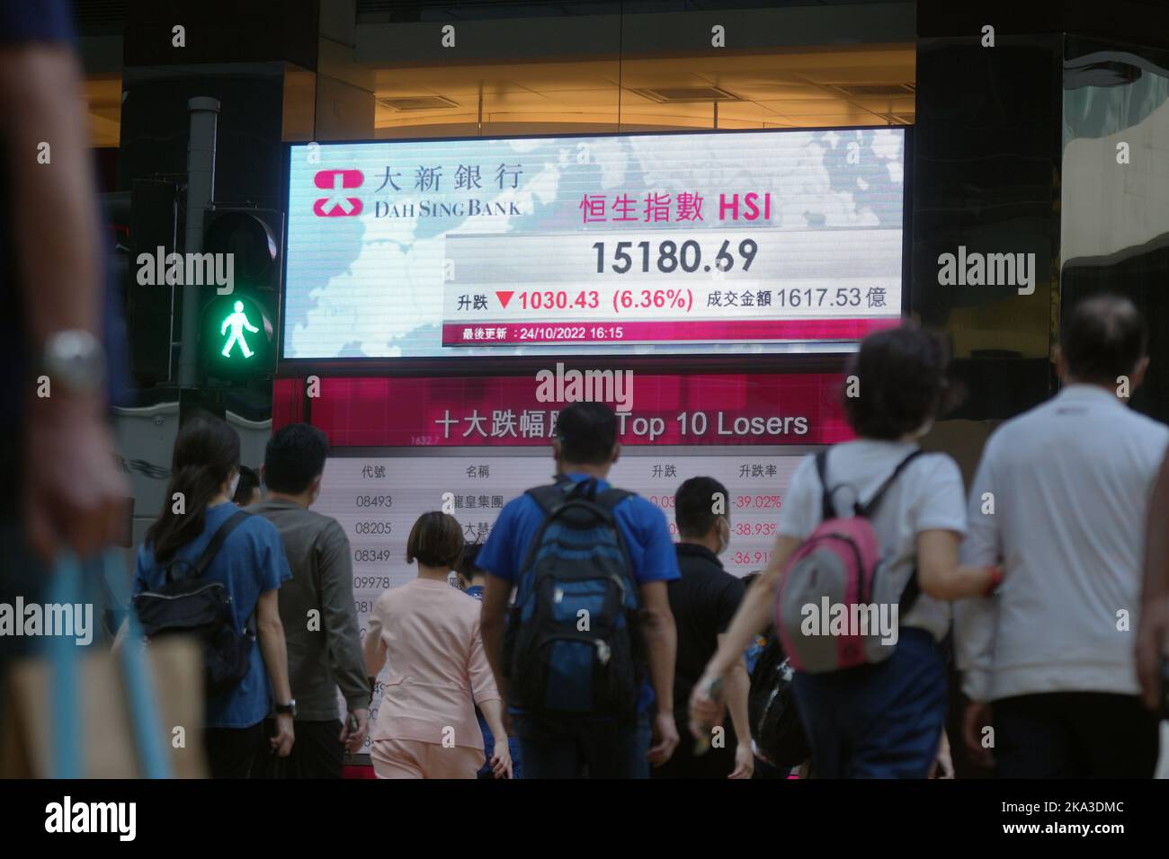 Pedestrians walk past an electronic billboard displaying the Hang Seng ...