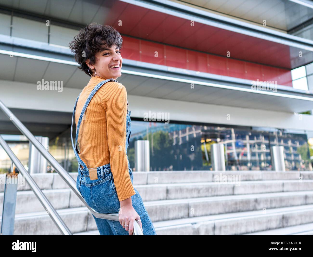 Side view ethnic female in denim overall looking over shoulder with ...