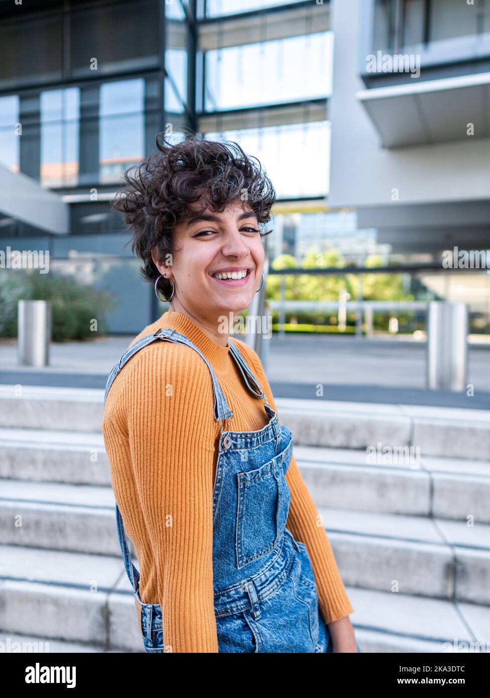 Side view ethnic female in denim overall looking over shoulder with ...