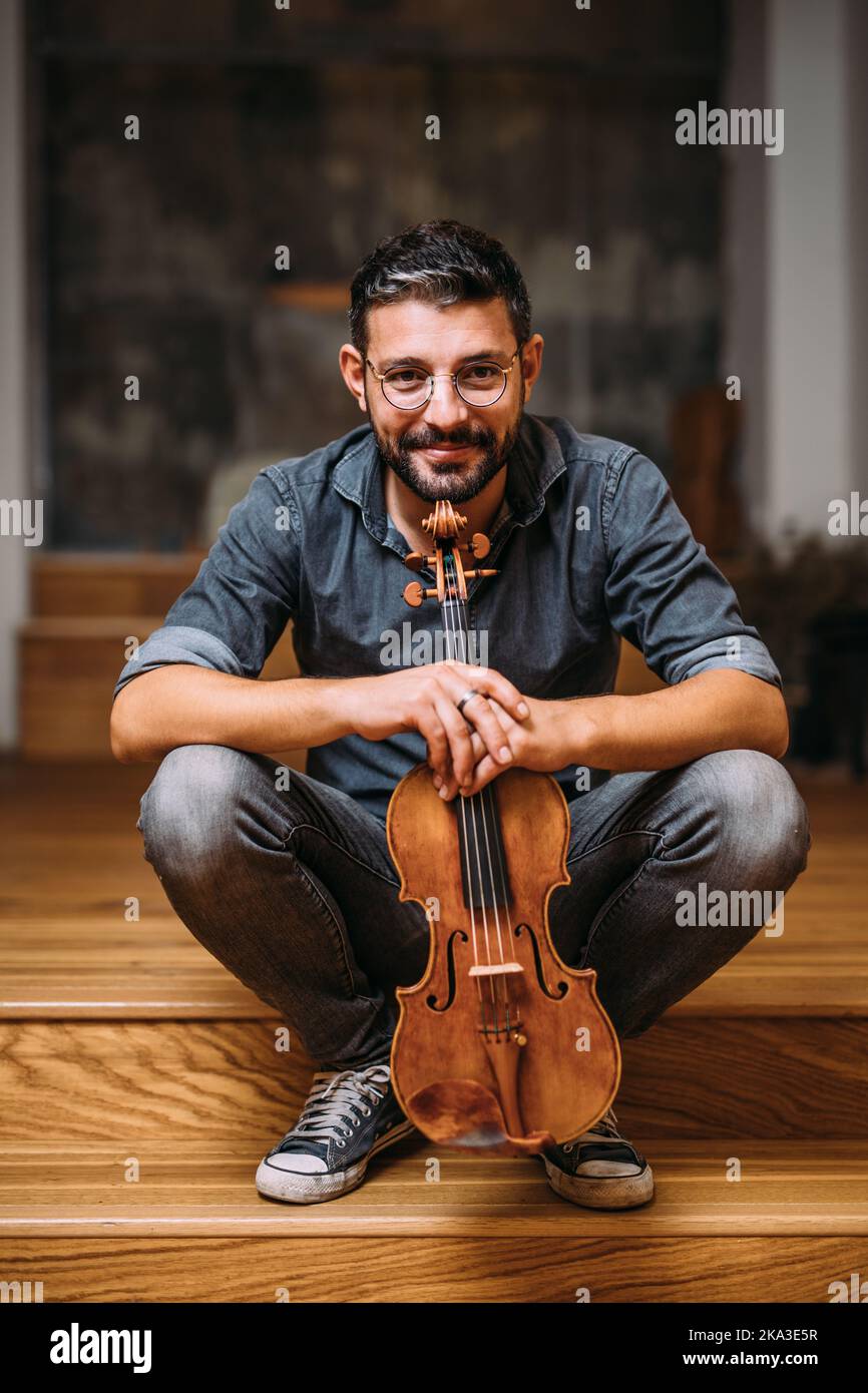Full body of adult calm male luthier in glasses holding traditional ...