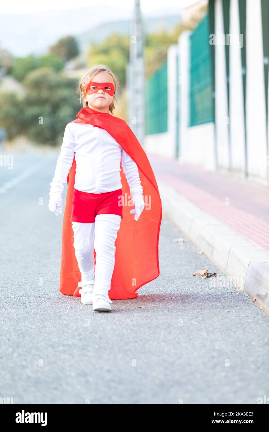 Full body of girl in superhero costume and mask looking at camera while ...
