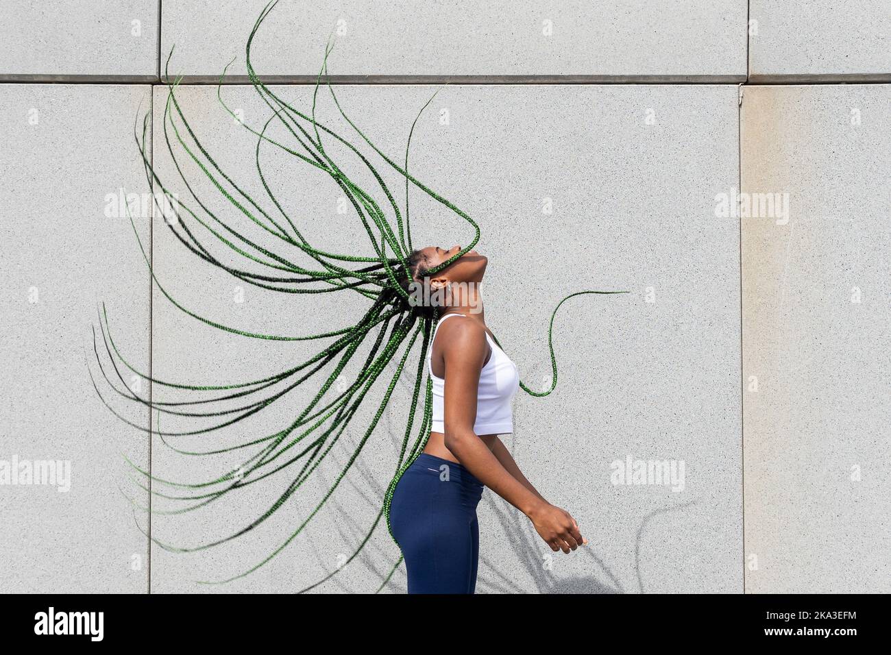 Side view of black young female in white top and blue denim shaking ...