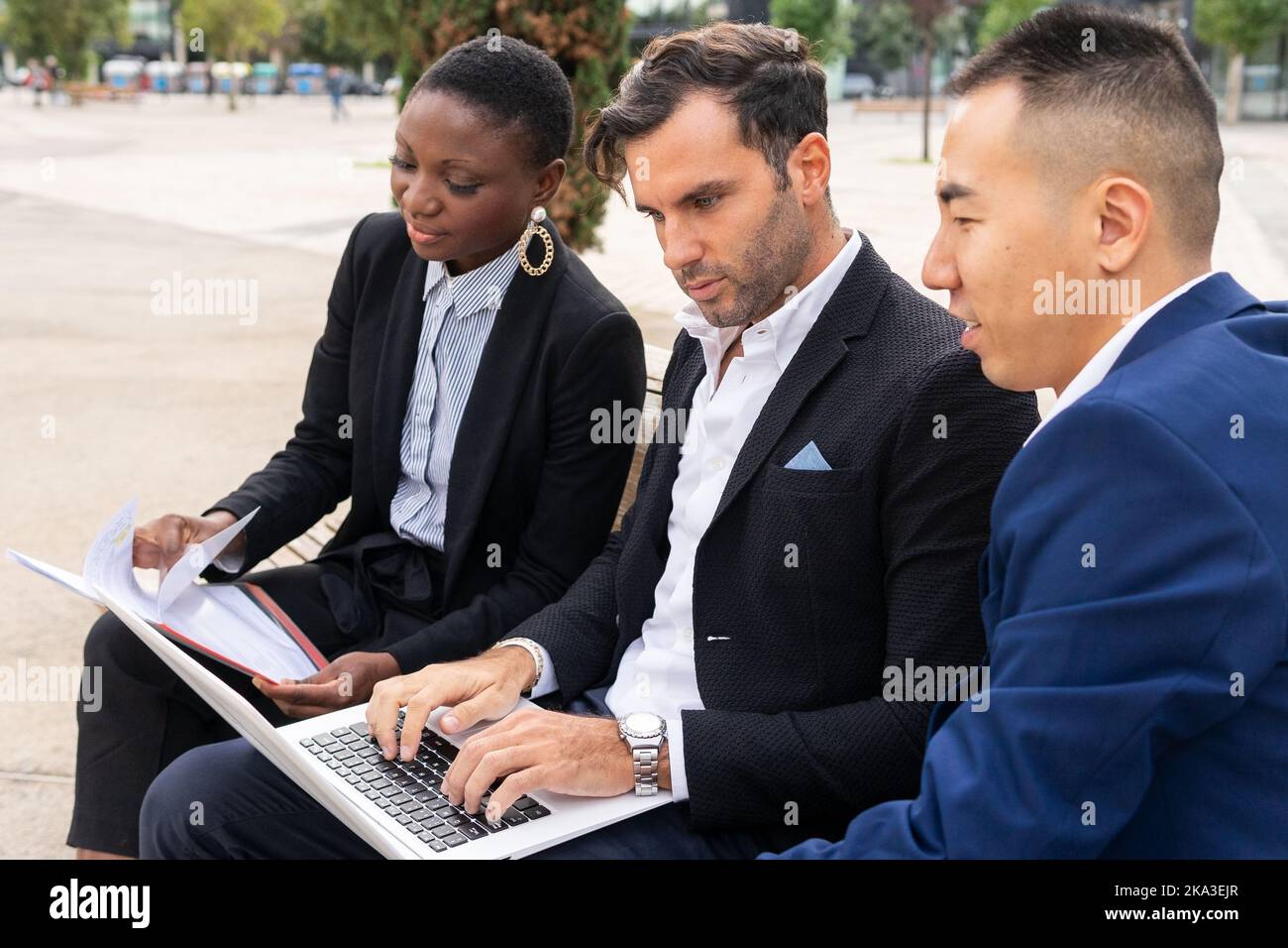 Group of multiracial coworkers in formal suits sitting on bench and ...