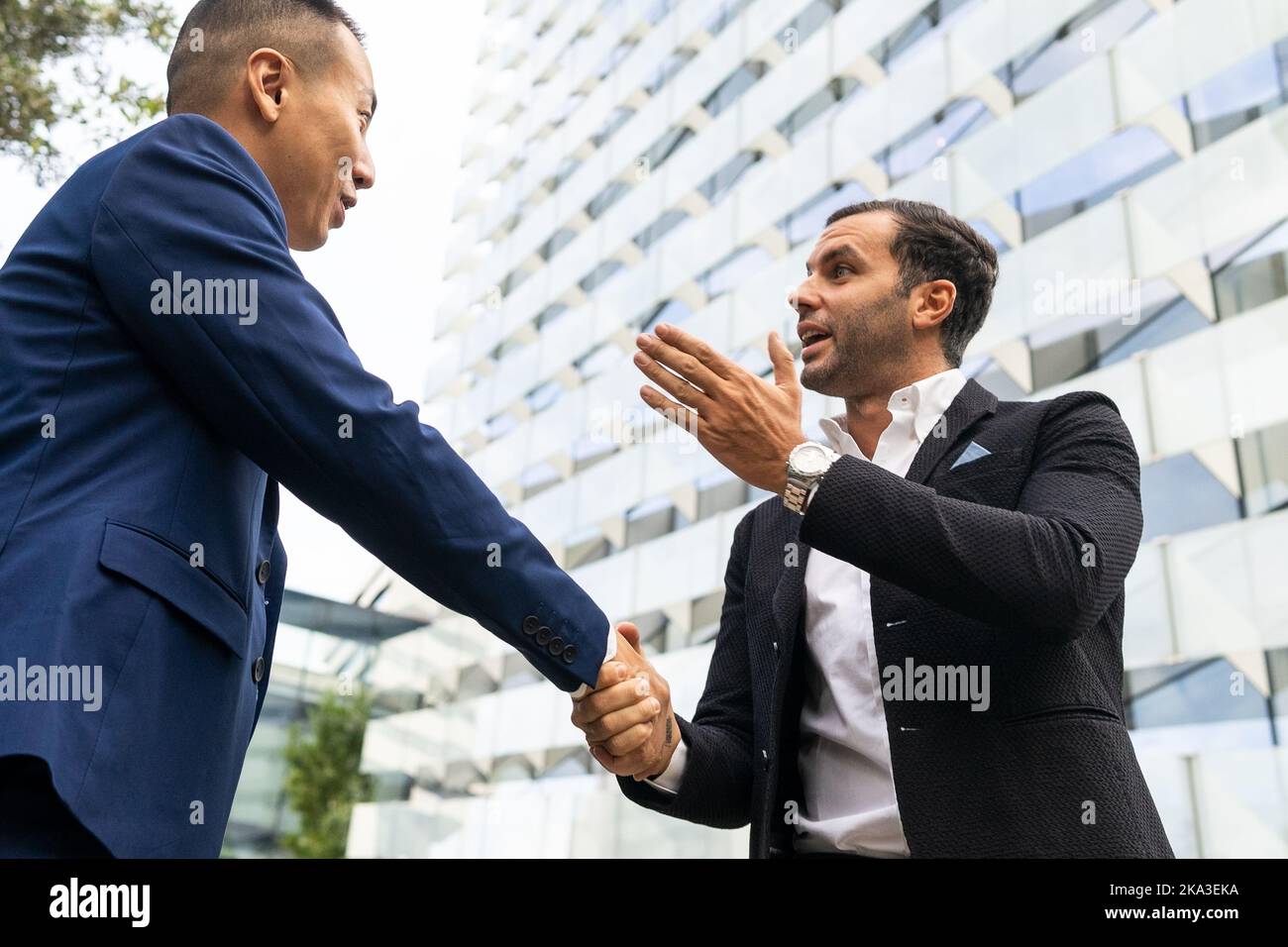 Low angle of positive multiracial businessmen in formal suits standing ...