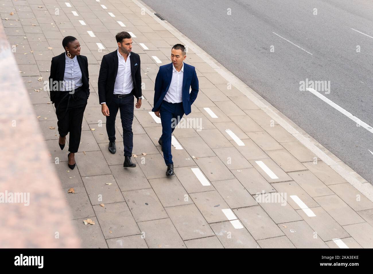 From above multiracial coworkers in formal outfits walking along paved ...