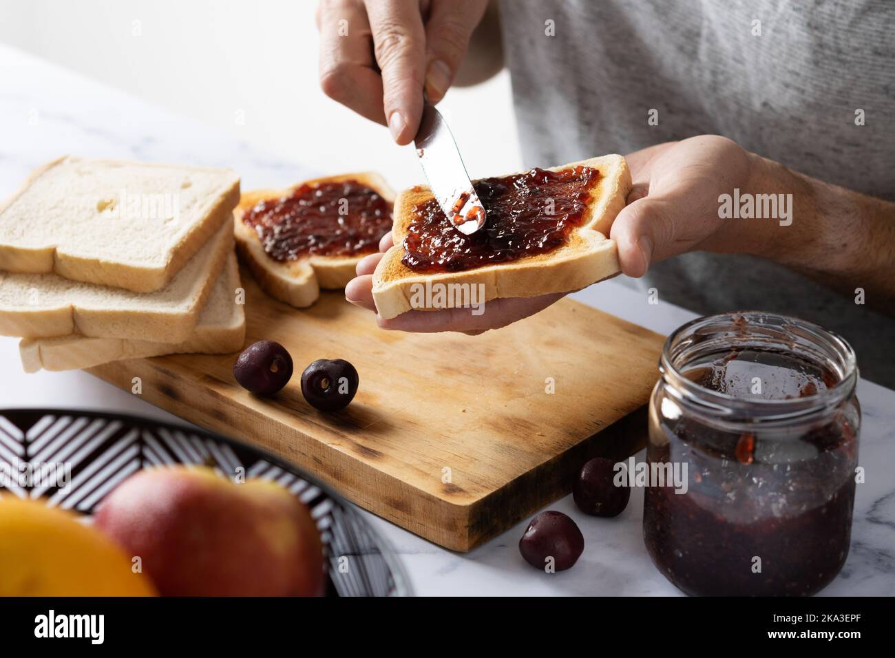 From above of crop anonymous man spreading sweet cherry jam on crispy ...