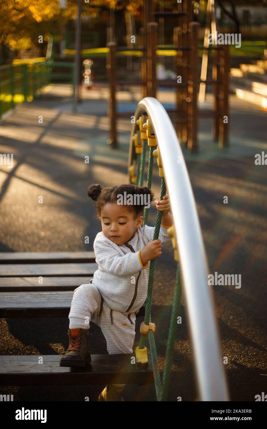 Adorable African American toddler with hair buns grasping railing and ...