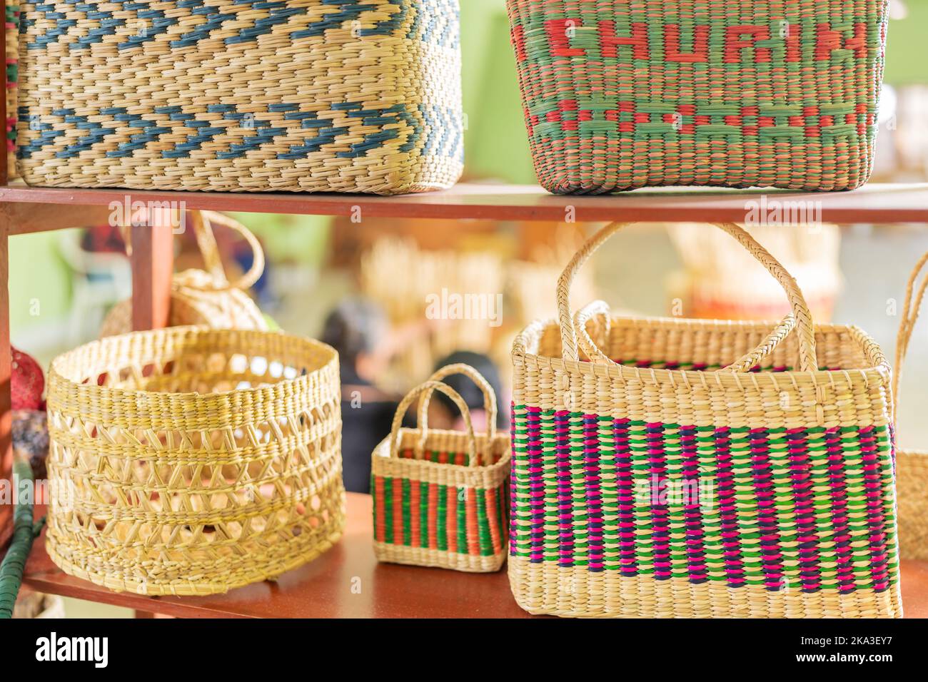 Many colorful wicker baskets placed on shelves on blurred background of ...