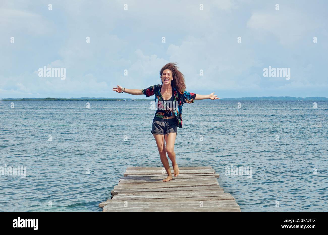 Female in shorts and top with long waving hair standing looking at ...