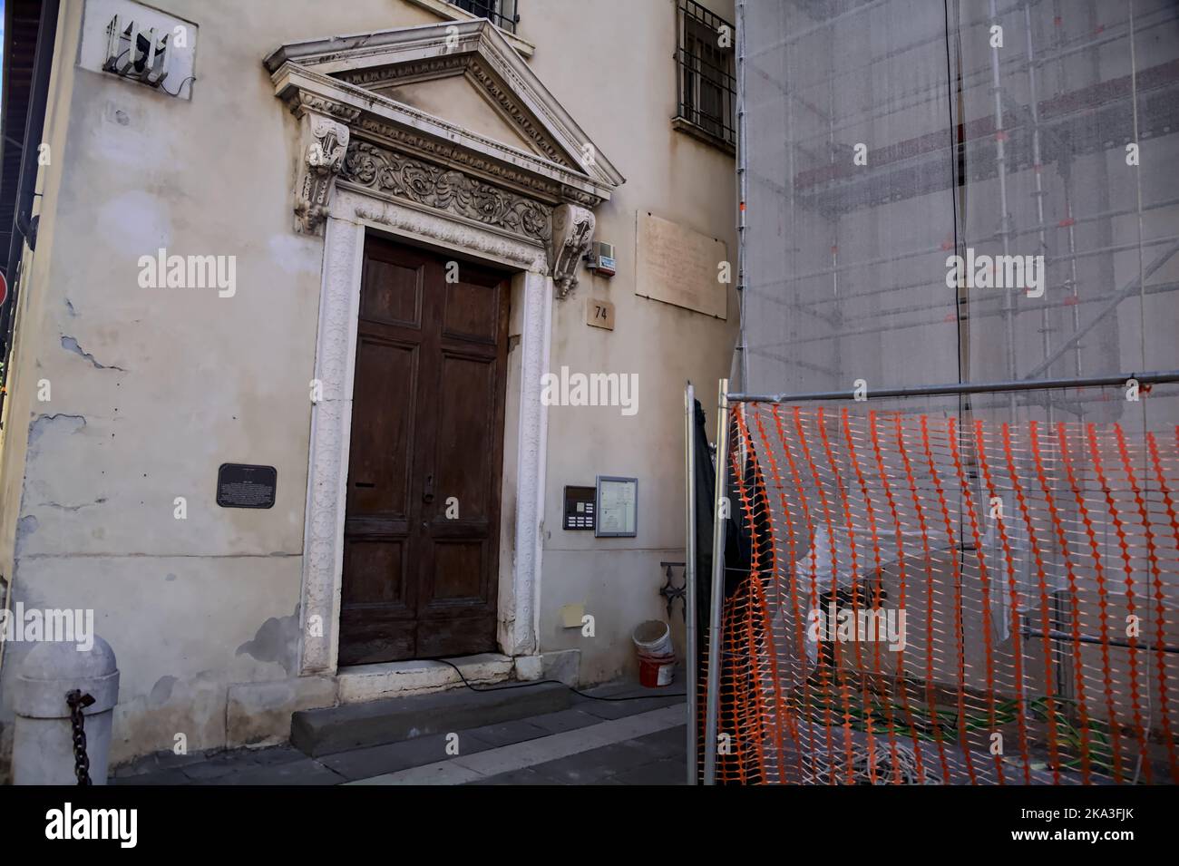 Side entrance of a church next to a barrier and a covered scaffolding ...