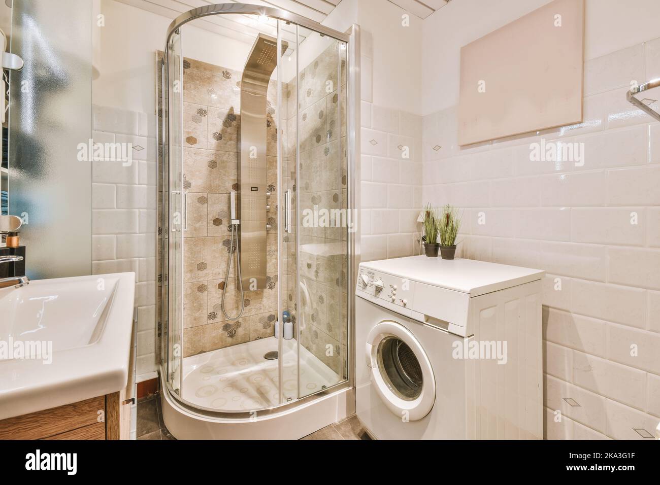 Sinks with mirrors and clean washing machine located near shower box ...