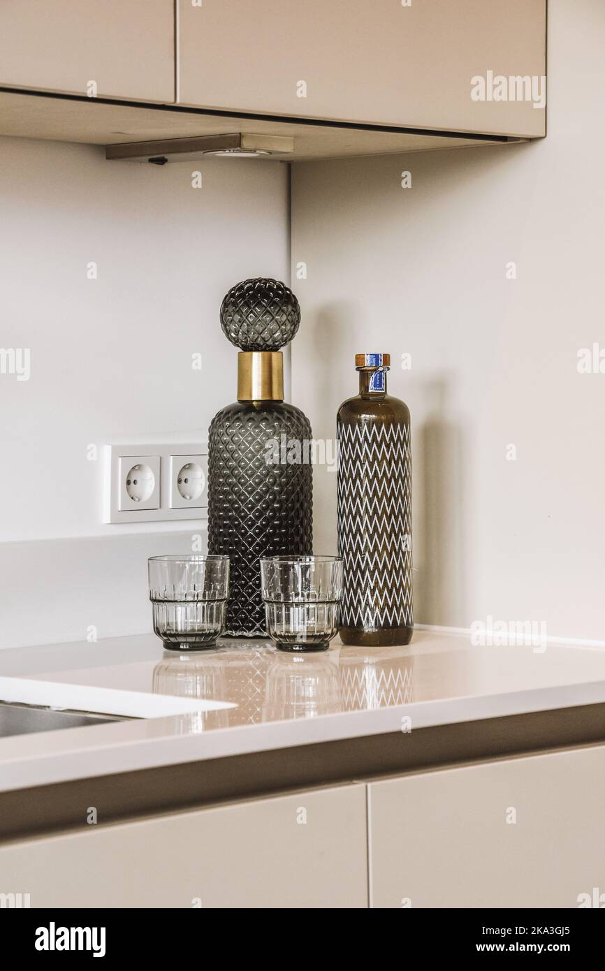 Bottles of alcoholic drink placed in light kitchen counter in modern ...