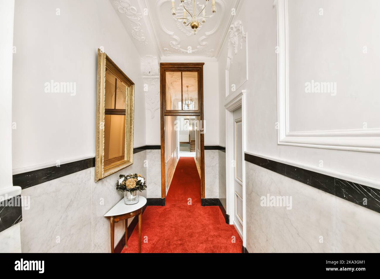 Stylish vintage hallway with red carpet with wooden door near golden ...