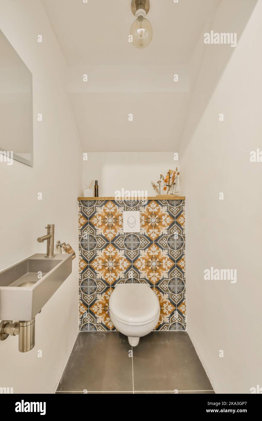 Ceramic toilet bowl and small sink in light restroom with white walls ...