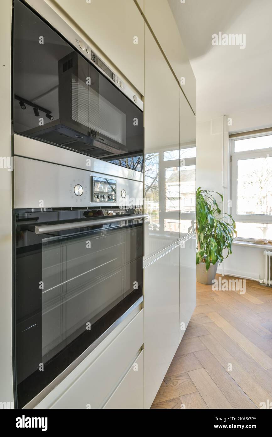 Contemporary built in ovens placed in modern kitchen with white ...