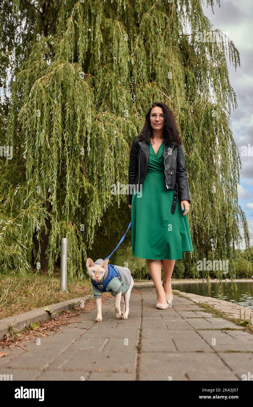 Woman walking with cat on a leash outdoor. Concept of Pet care, cat on ...