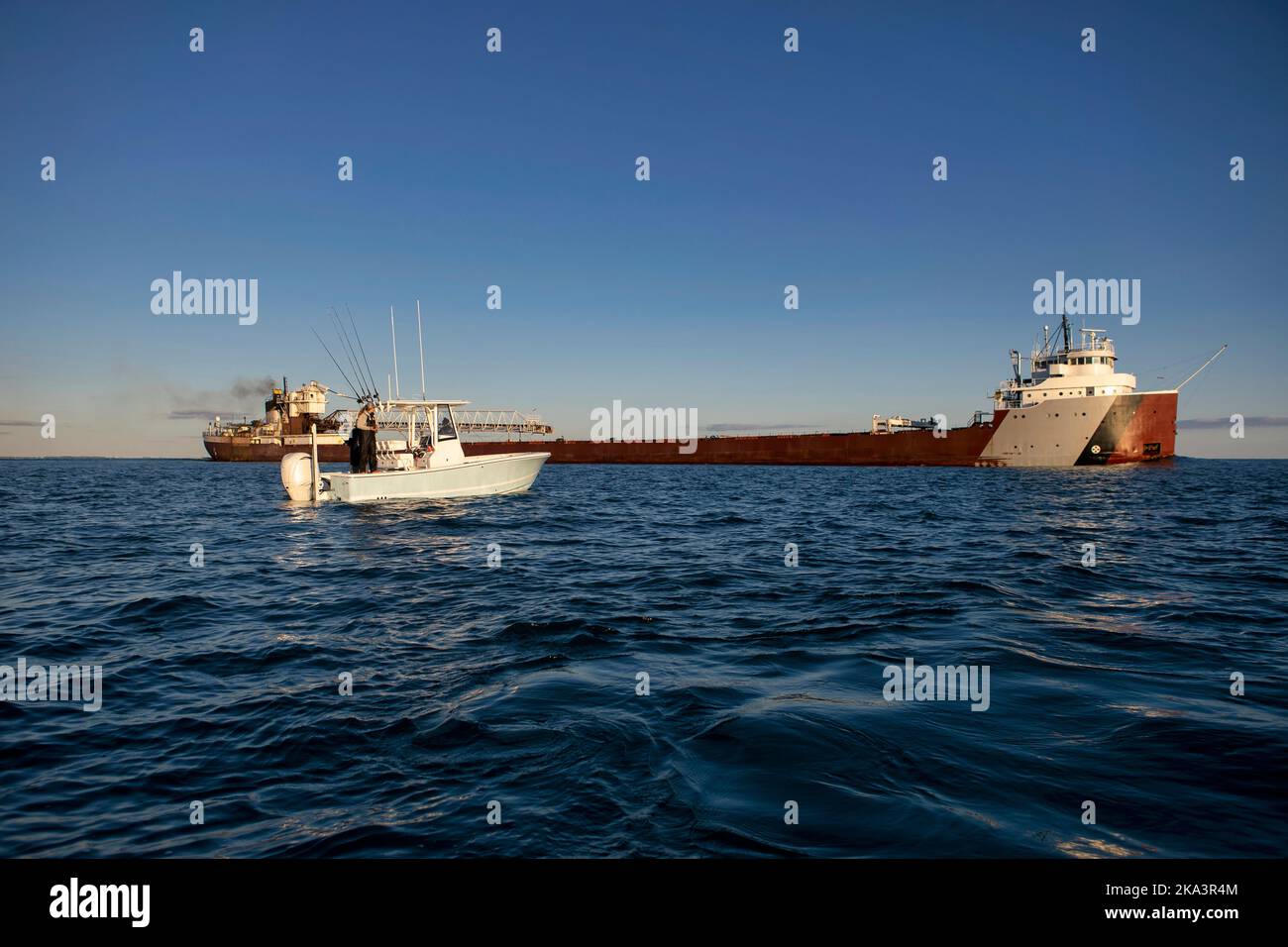 A lake freighter on the horizon with a fishing boat nearby Stock Photo ...