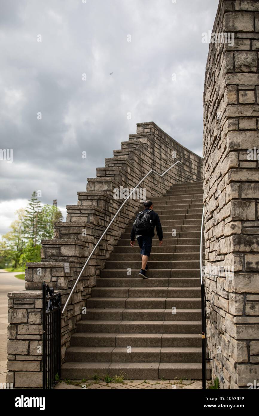 A vertical shot of a male seen from behind, walking up the stairs of a ...