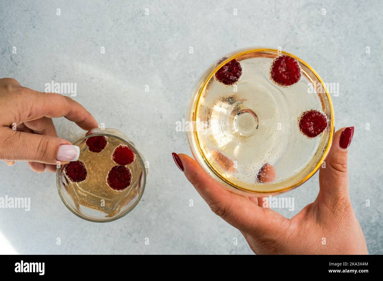 Overhead view of two women drinking glasses of champagne and cocktails ...