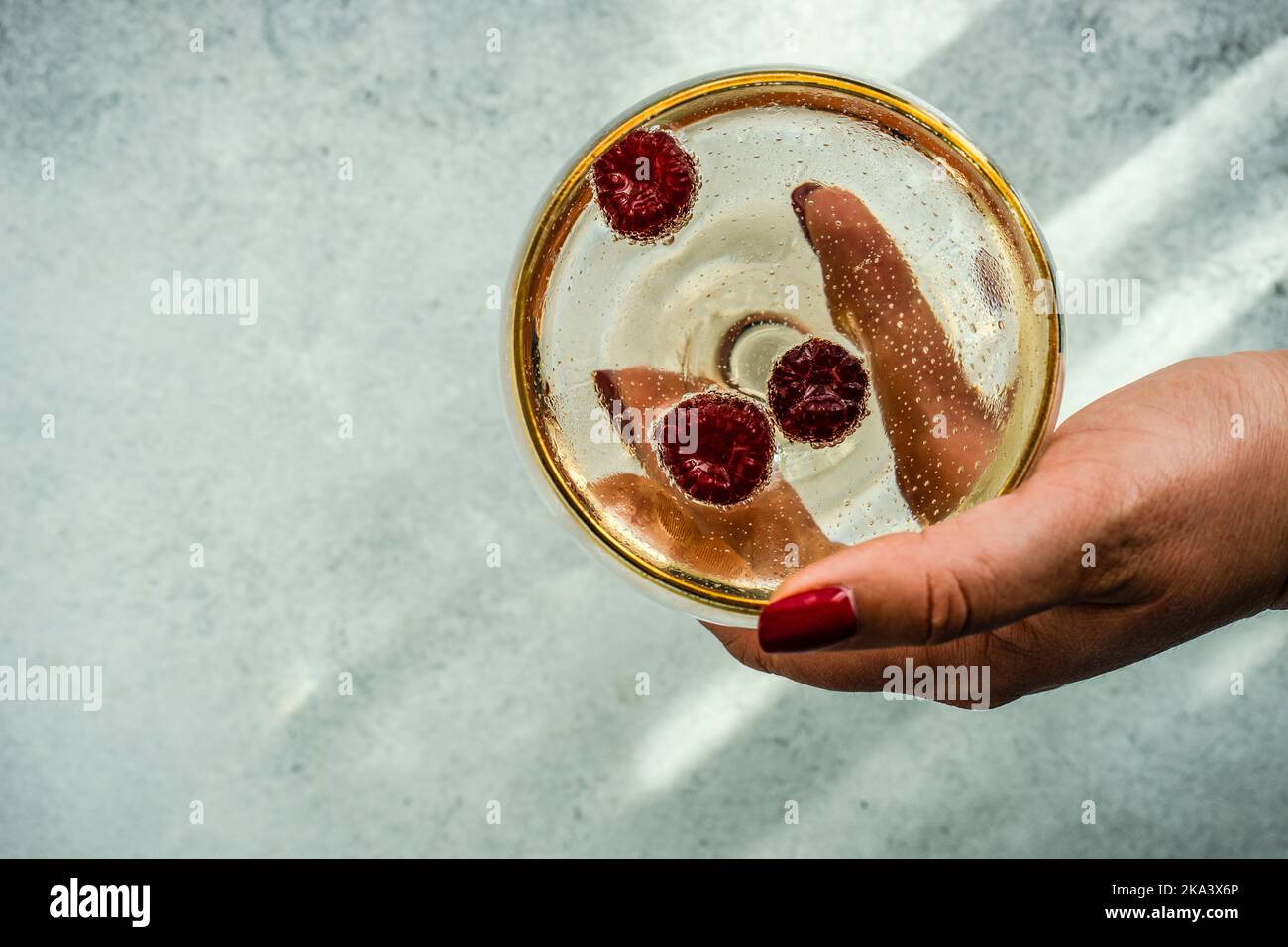 Overhead view of a woman holding a champagne glass with fresh ...