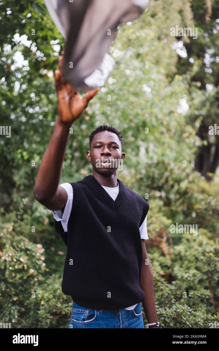 Young African man outdoor throwing plastic trash bag in the air, street ...