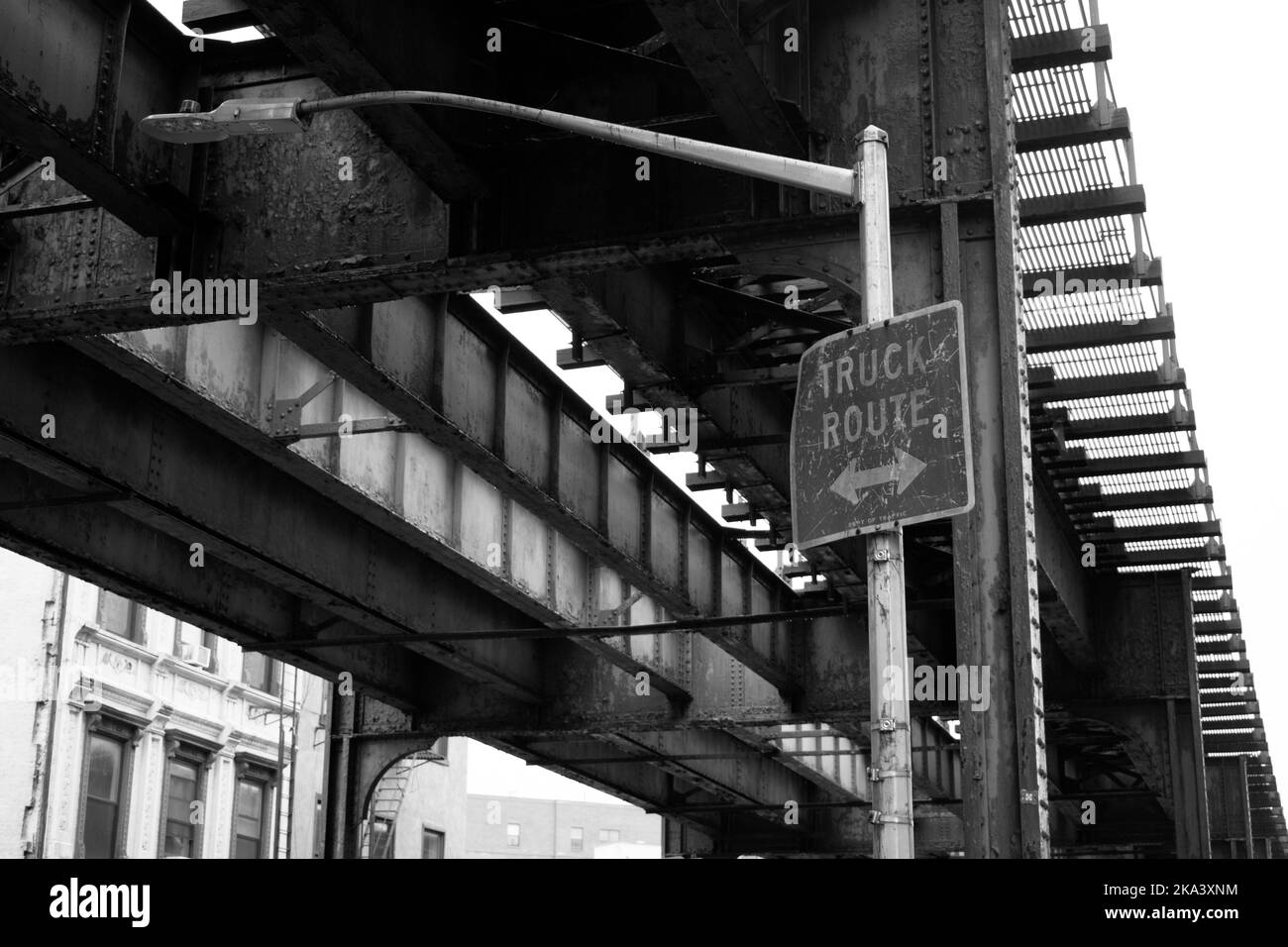 A grayscale shot of an old sign truck route on a light pole under a ...