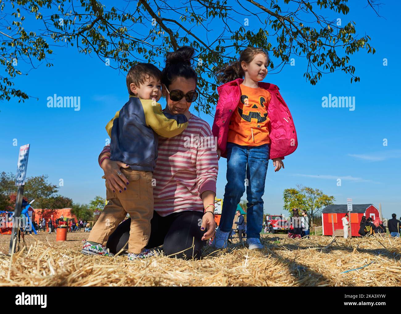 Mom with kids on top of a hay stack at the farm fair on Halloween Stock ...