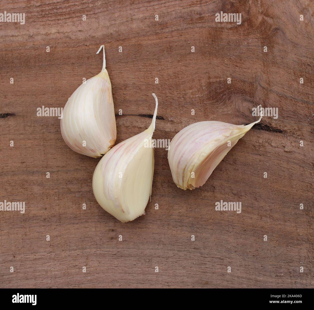 Three Large Garlic Cloves on a Rustic Wood Background Stock Photo - Alamy