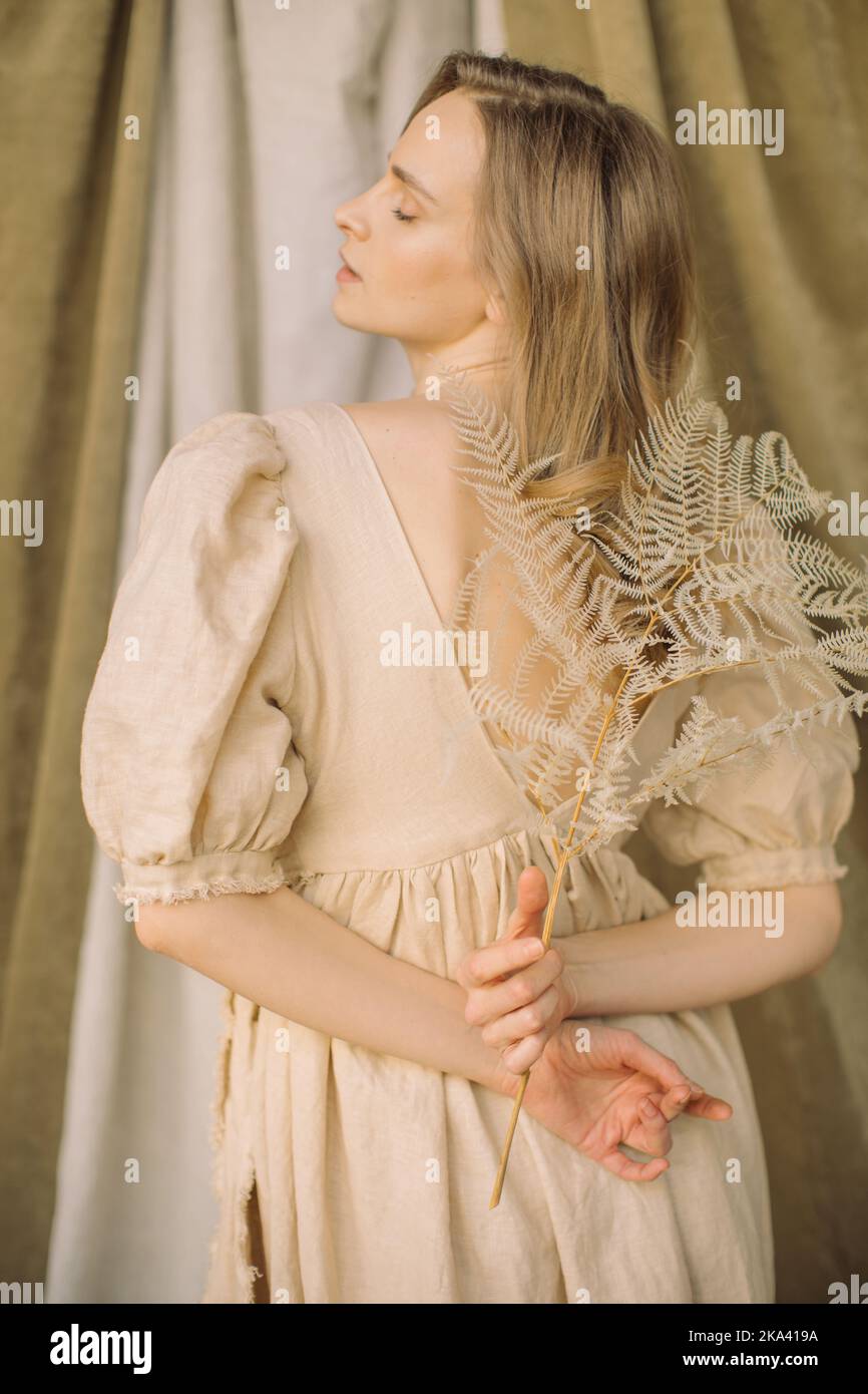 Rear view portrait of a beautiful woman holding a decorative leaf ...