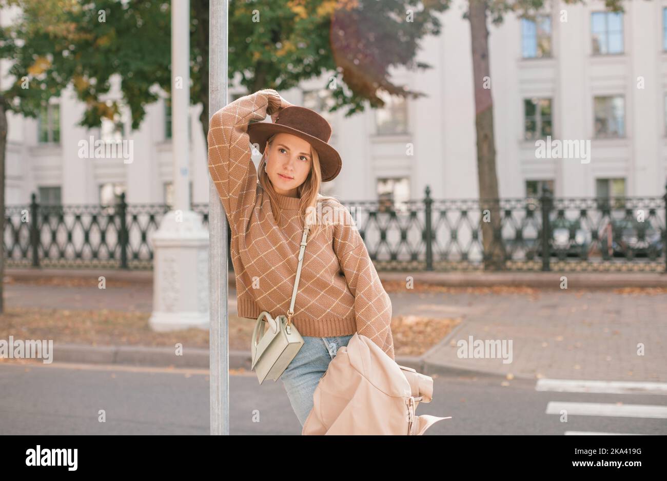 Portrait of a beautiful woman leaning against a lamp post in the street ...