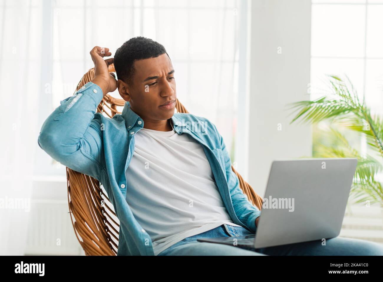 Pensive sad young african american man typing on computer in light ...
