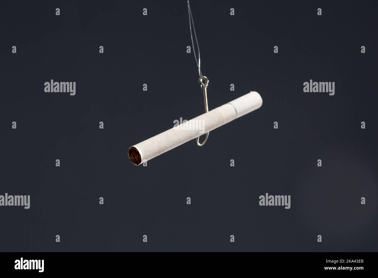A view of cigarette hanging from metal hook isolated in black ...