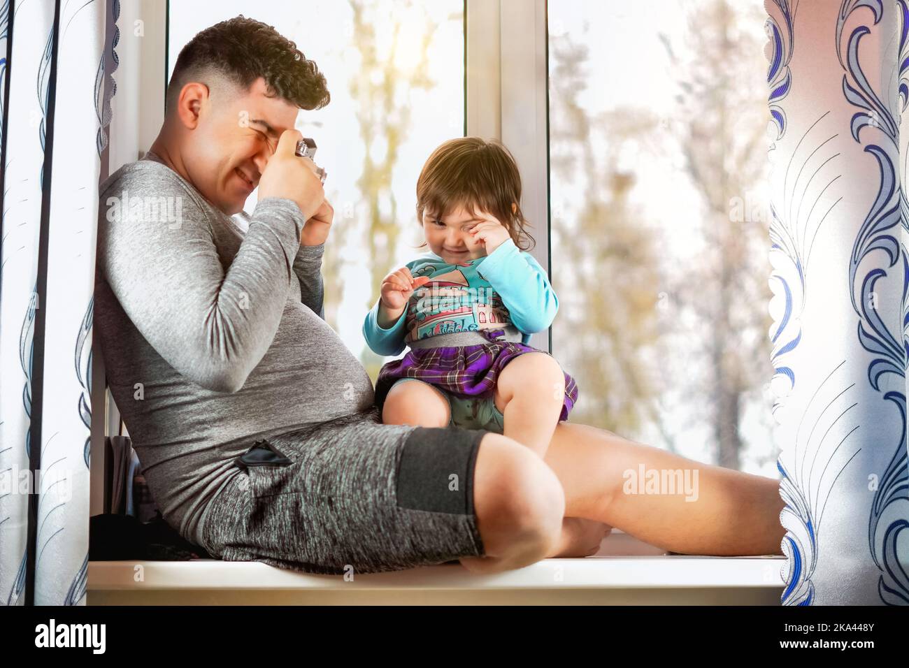 A close up father with his daughter playing sitting on a window Stock ...