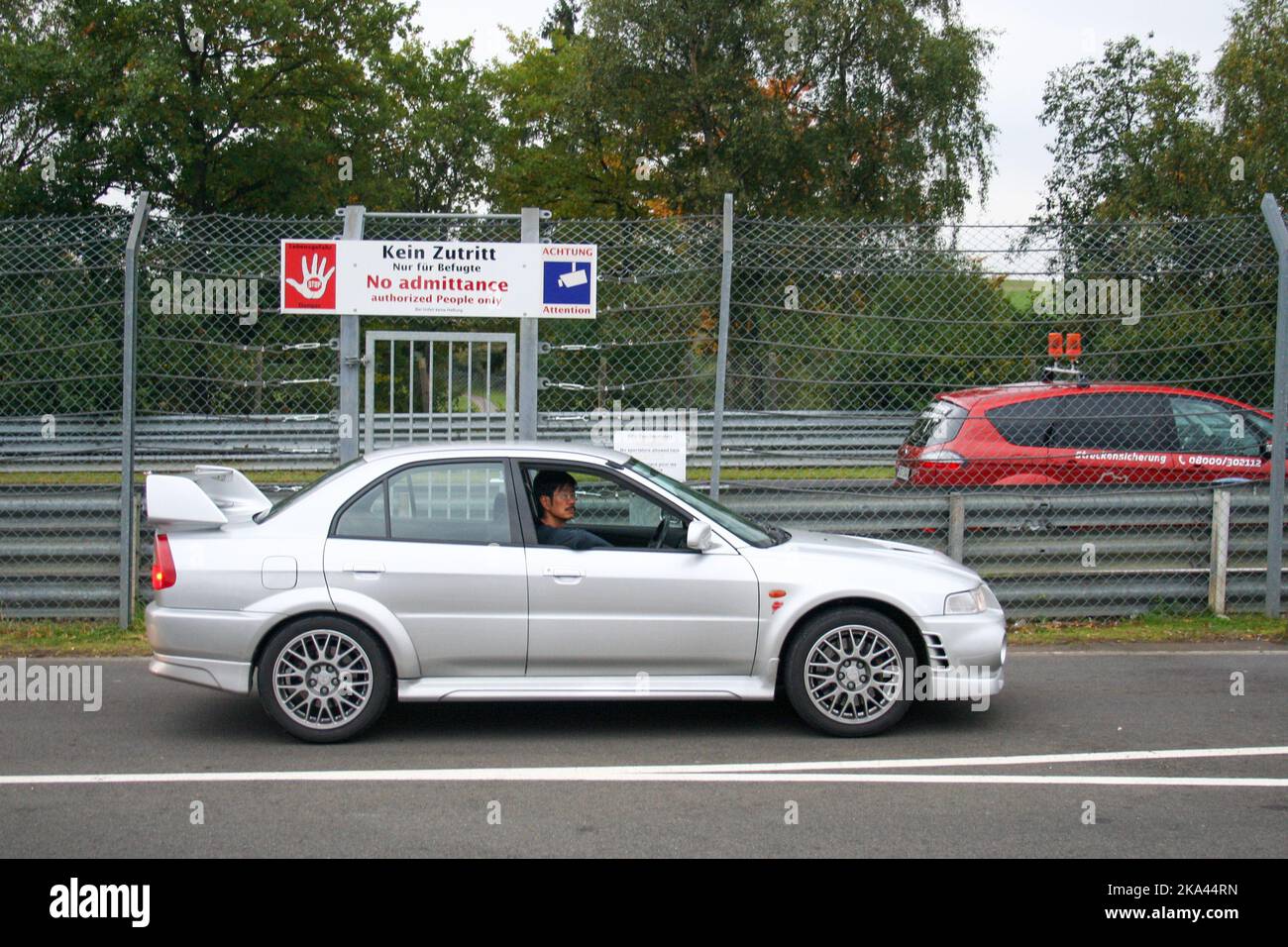 A closeup of a silver Mitsubishi Lancer Evo and driver waiting to race ...