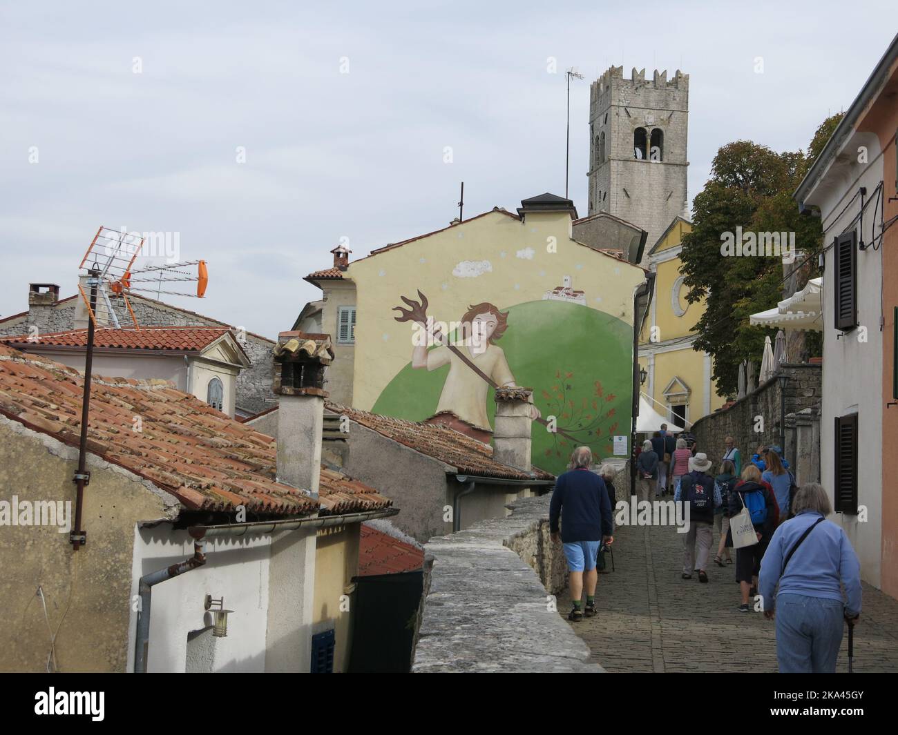 Tourists walk along a cobbled street in the medieval town of Motovun ...