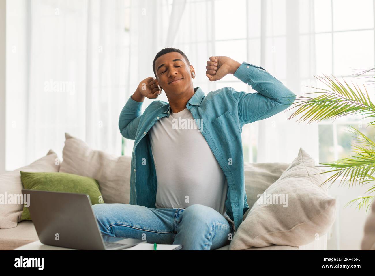 Glad relaxed young african american man in wireless headphones with ...