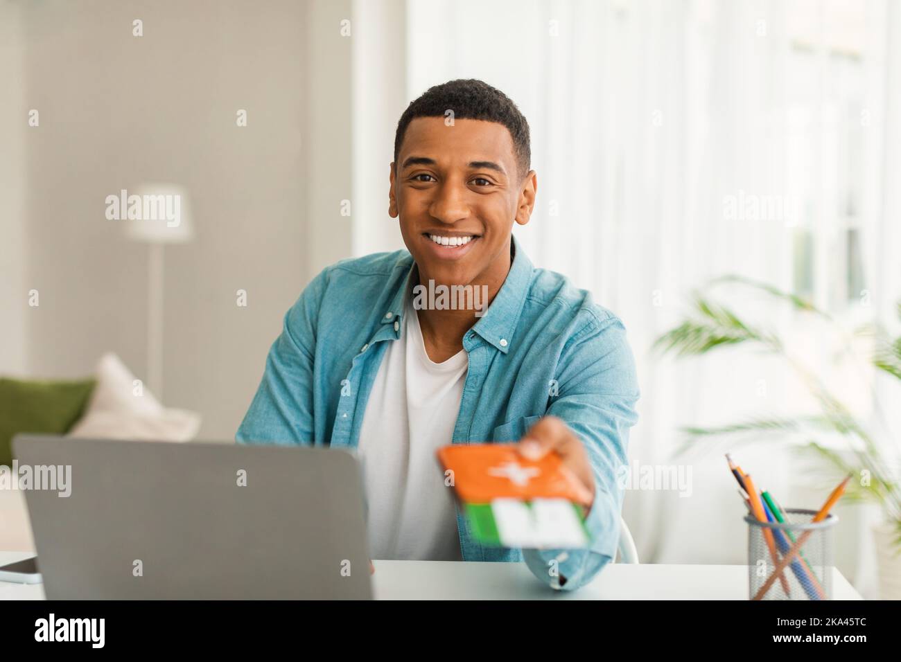 Glad handsome young african american man in casual with computer gives ...