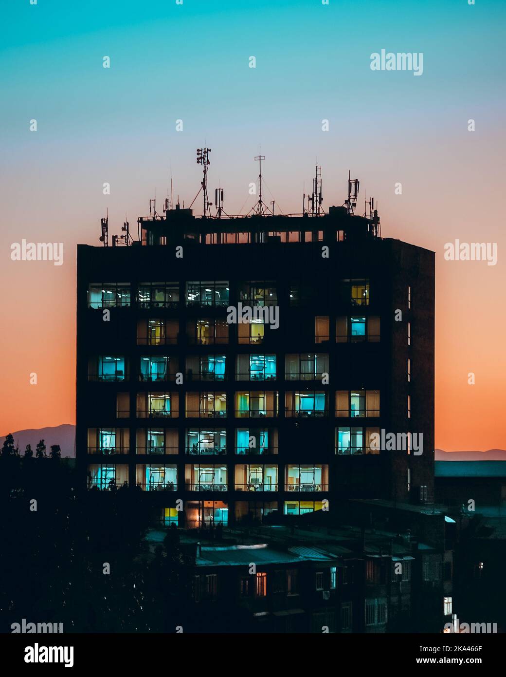 A vertical view of an illuminated apartment building against pastel ...